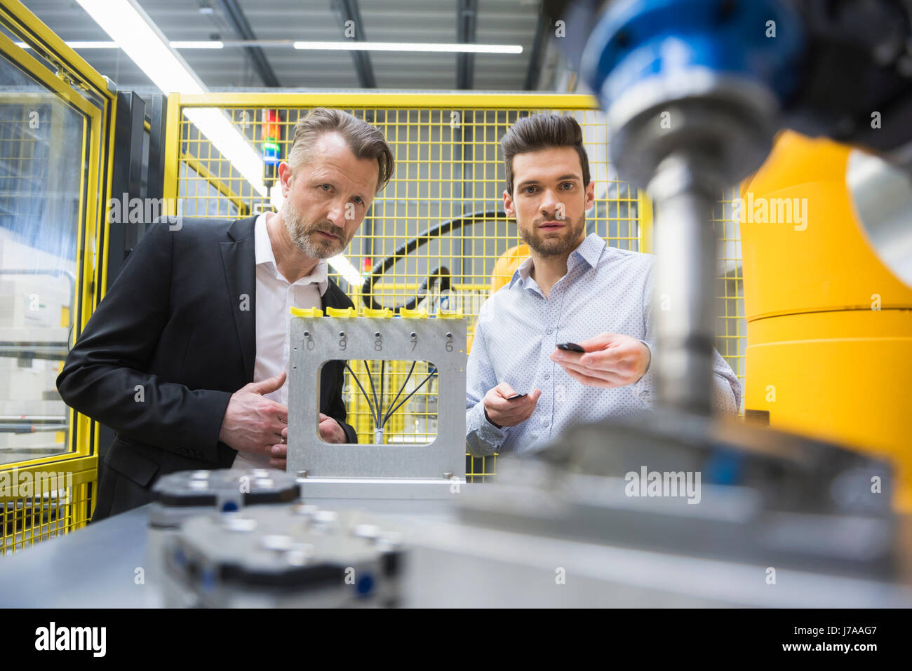 Two businessman observing industrial robots in factory Stock Photo - Alamy