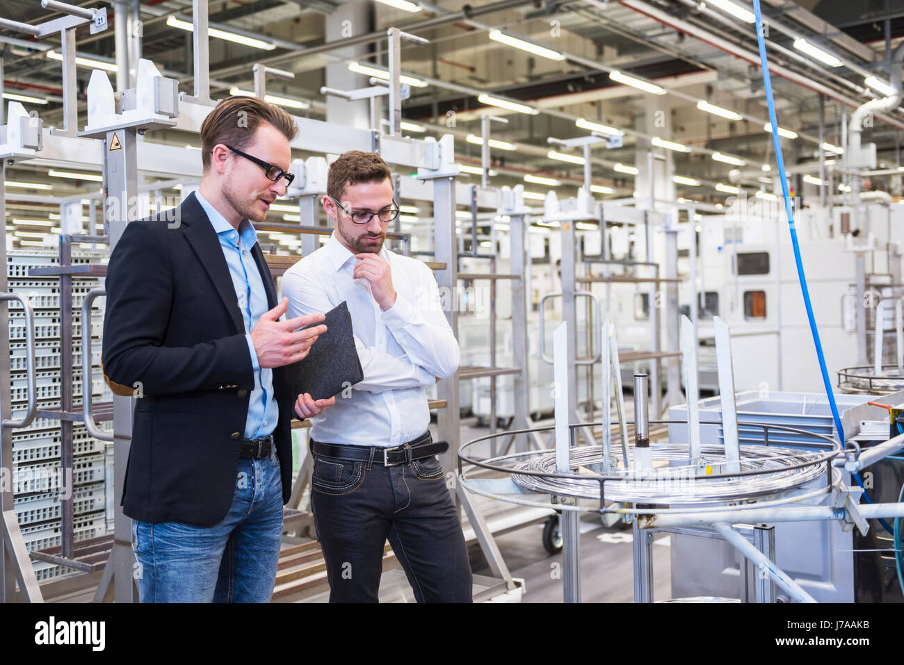 Two men talking in factory shop floor Stock Photo - Alamy
