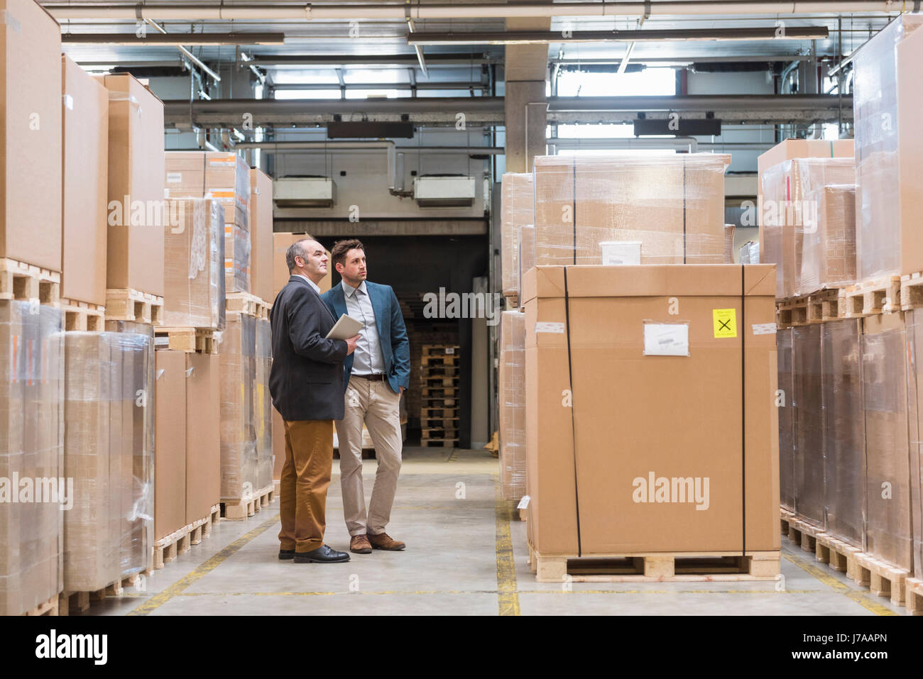 Two men standing in factory warehouse Stock Photo - Alamy