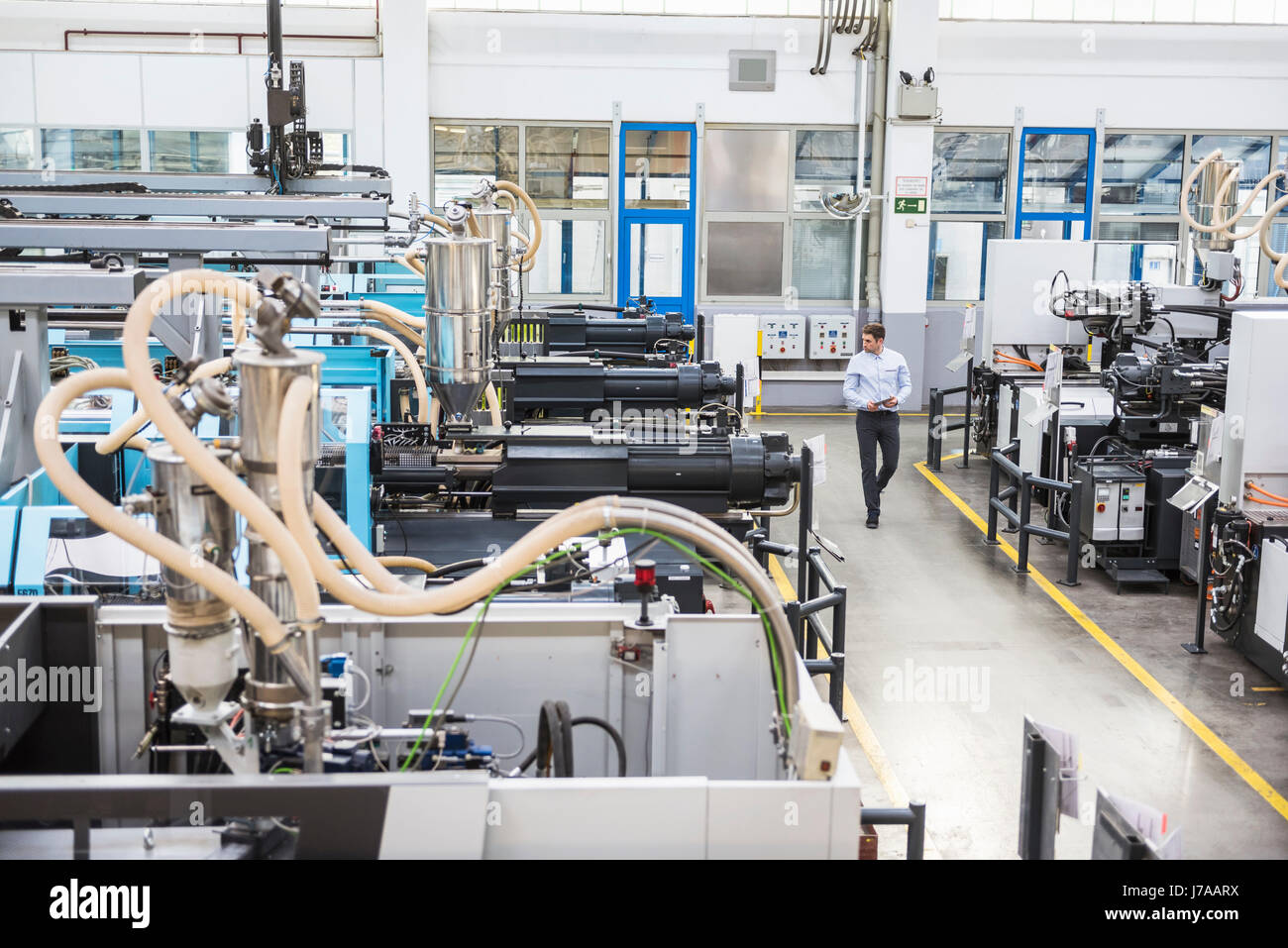 Man with tablet walking in factory shop floor Stock Photo - Alamy