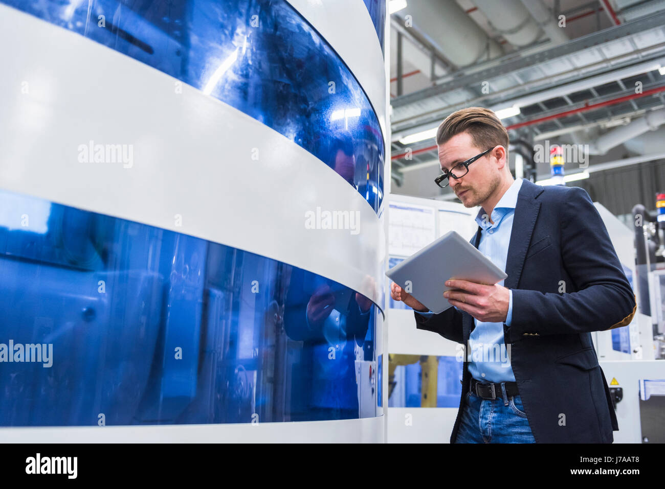 Man holding tablet looking at machine in factory shop floor Stock Photo ...