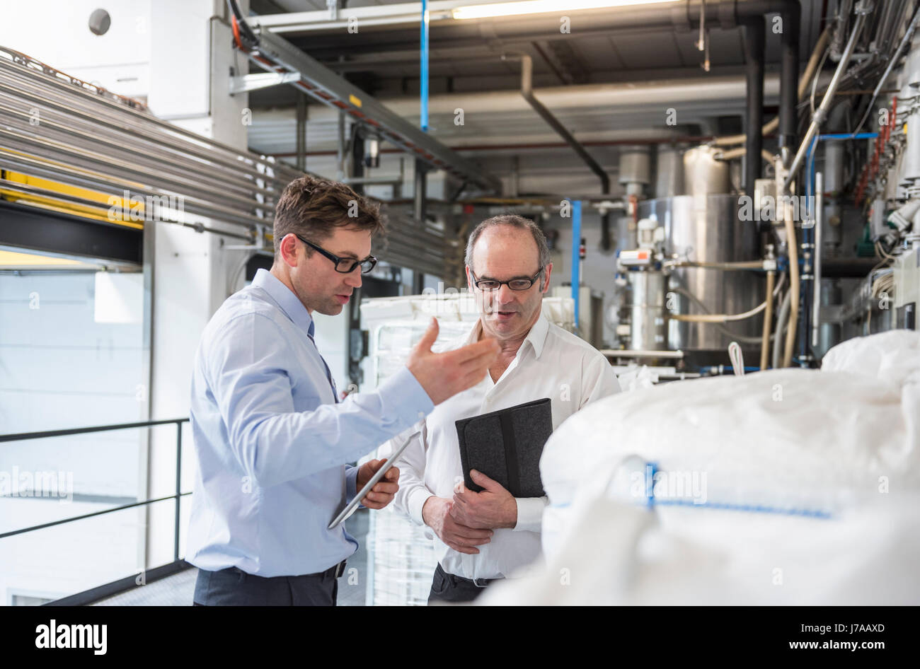 Two men talking about materials in factory Stock Photo - Alamy
