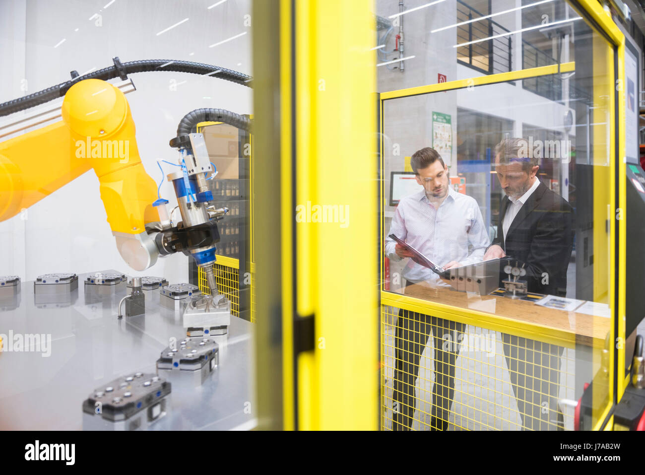 Two businessman observing industrial robots in factory Stock Photo - Alamy