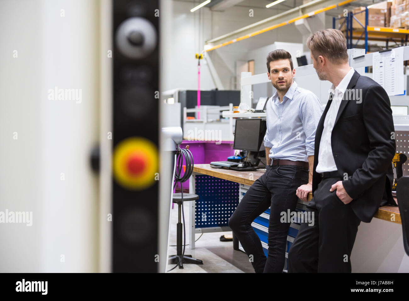 Two men talking in factory shop floor Stock Photo - Alamy