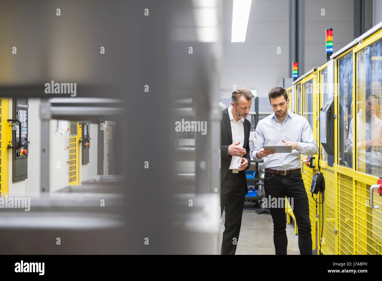 Two businessman observing industrial robots in factory Stock Photo - Alamy