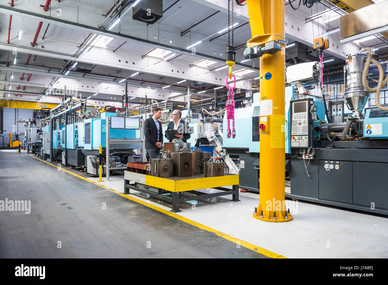 Two men with documents talking in factory shop floor Stock Photo - Alamy
