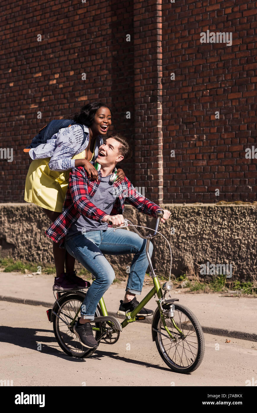 Young man riding bicycle with his girlfriend standing on rack Stock ...