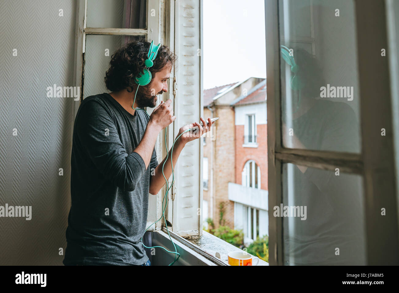 Man talking on cell phone in his room by the window Stock Photo - Alamy