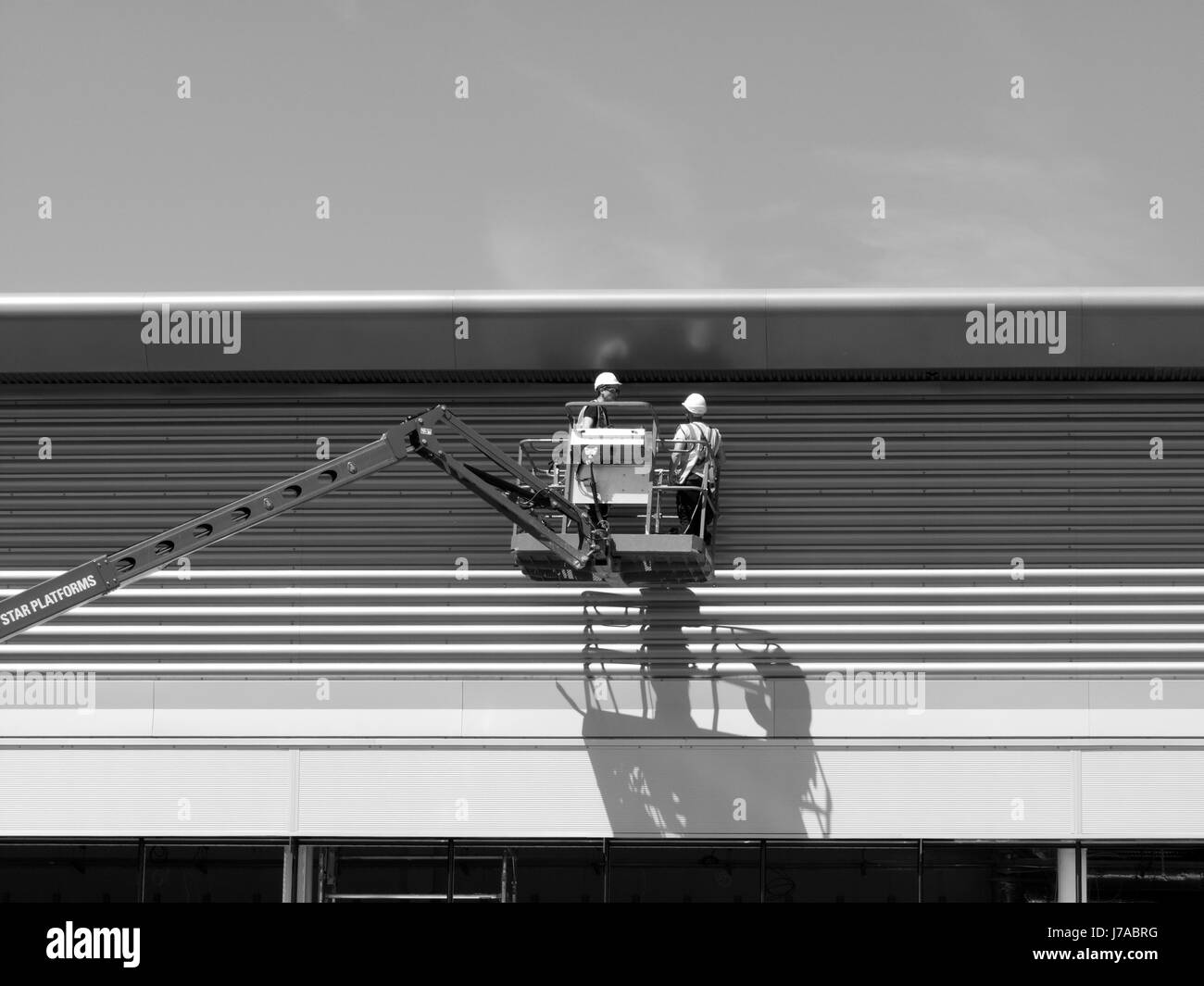 construction workers on mobile access platform installing on cladding ...