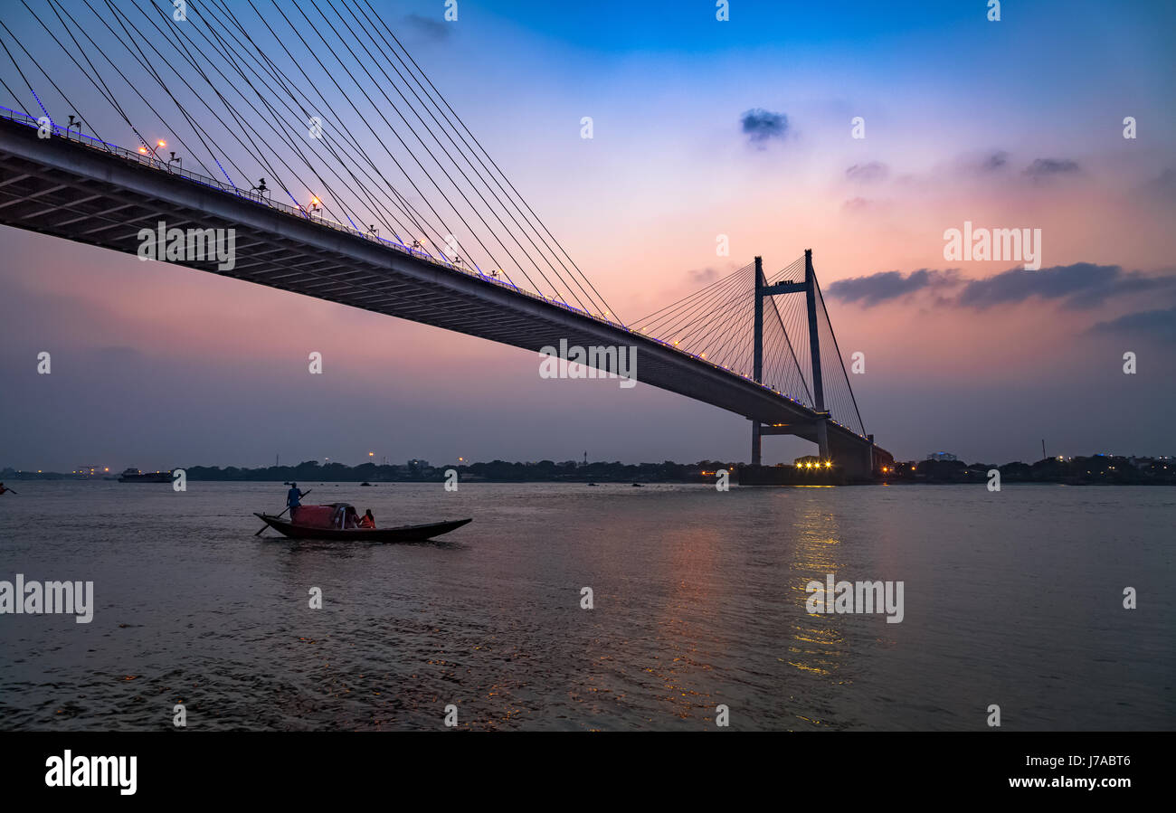 Vidyasagar Setu bridge at twilight with a wooden boat on river Hooghly ...