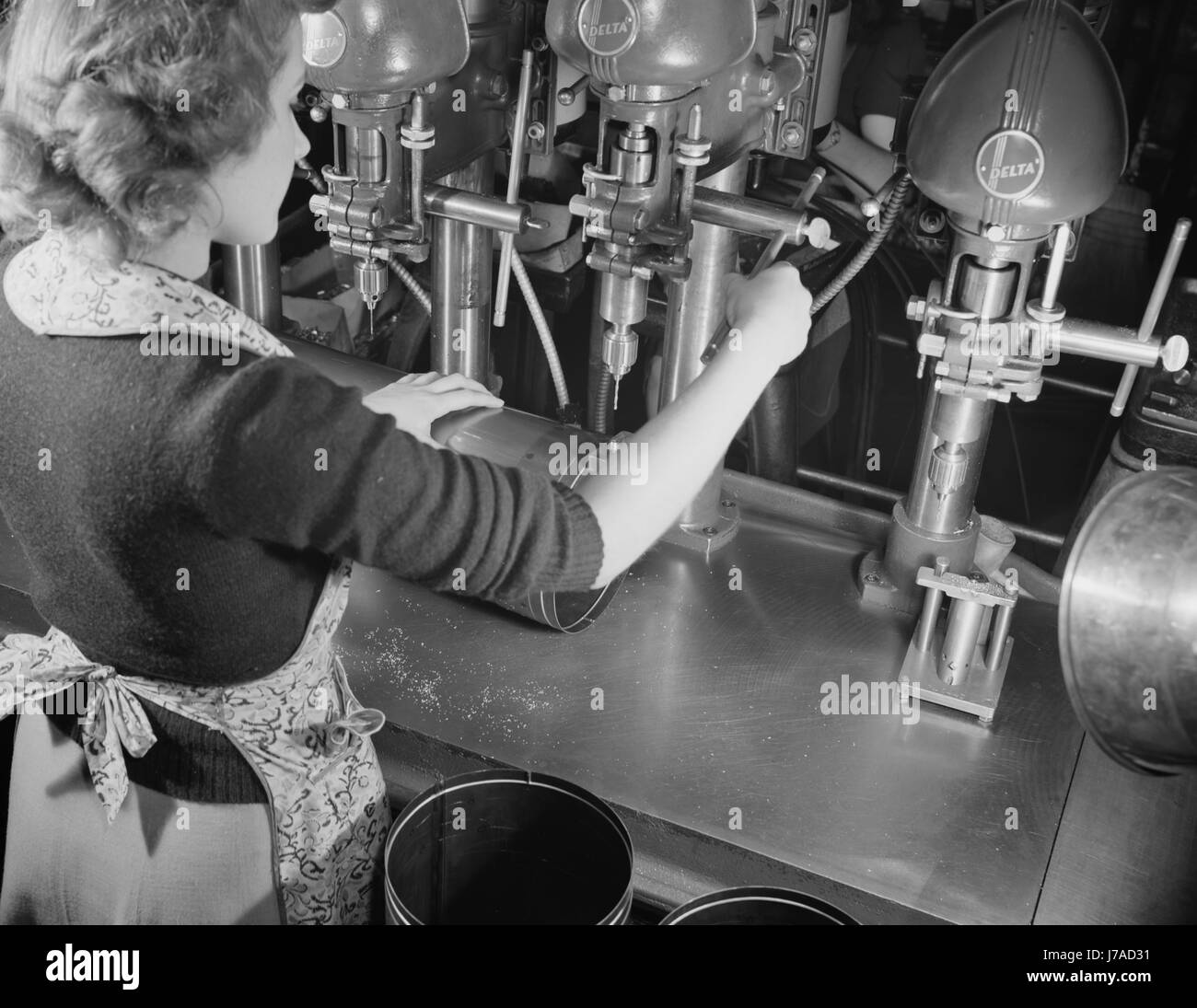 Woman worker drilling holes in parachute flare casings at a factory ...