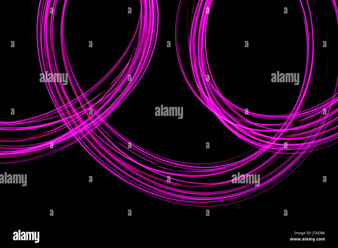 Long exposure photograph of neon pink colour in an abstract loop ...