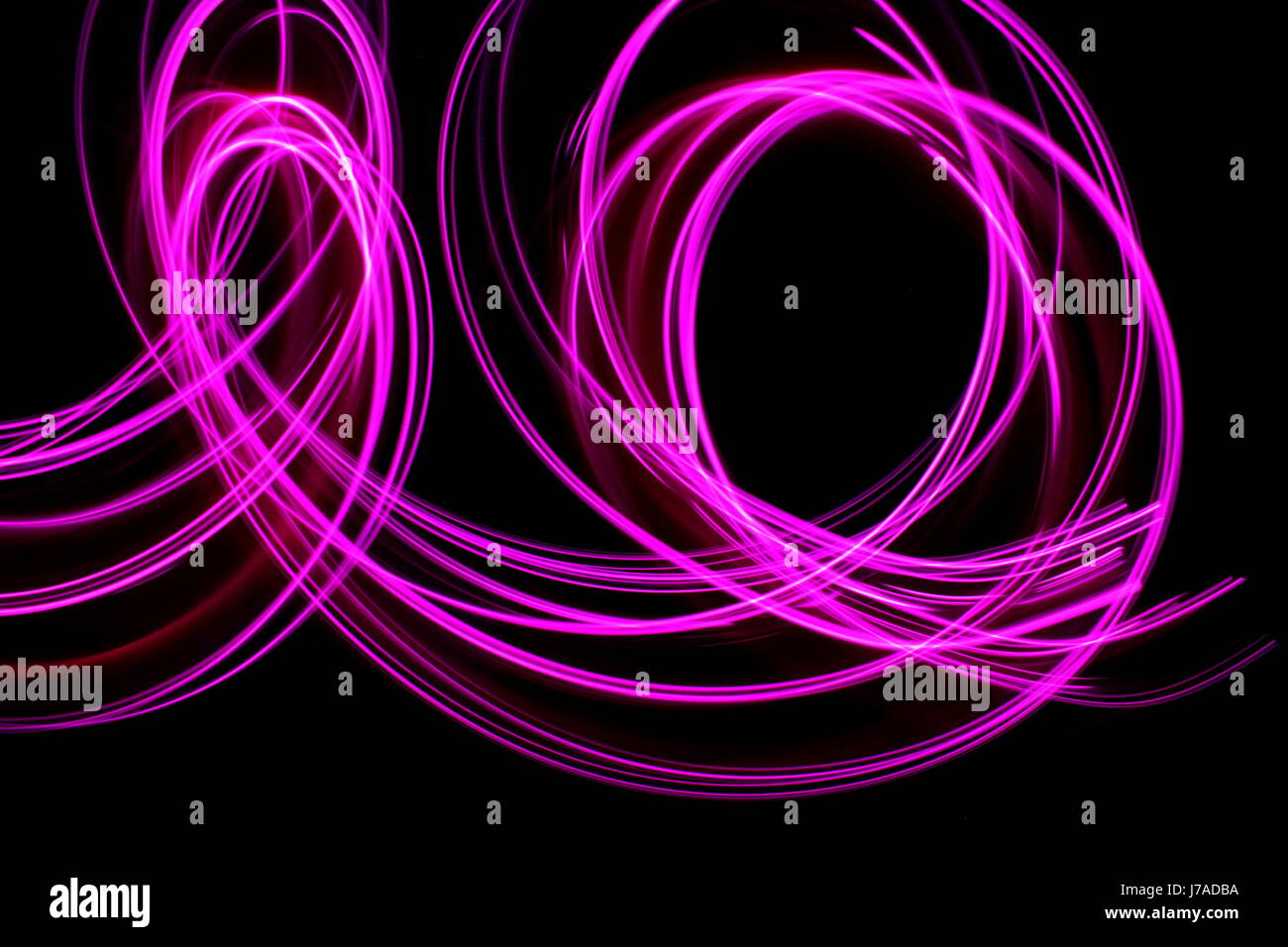 Long exposure photograph of neon pink colour in an abstract loop ...