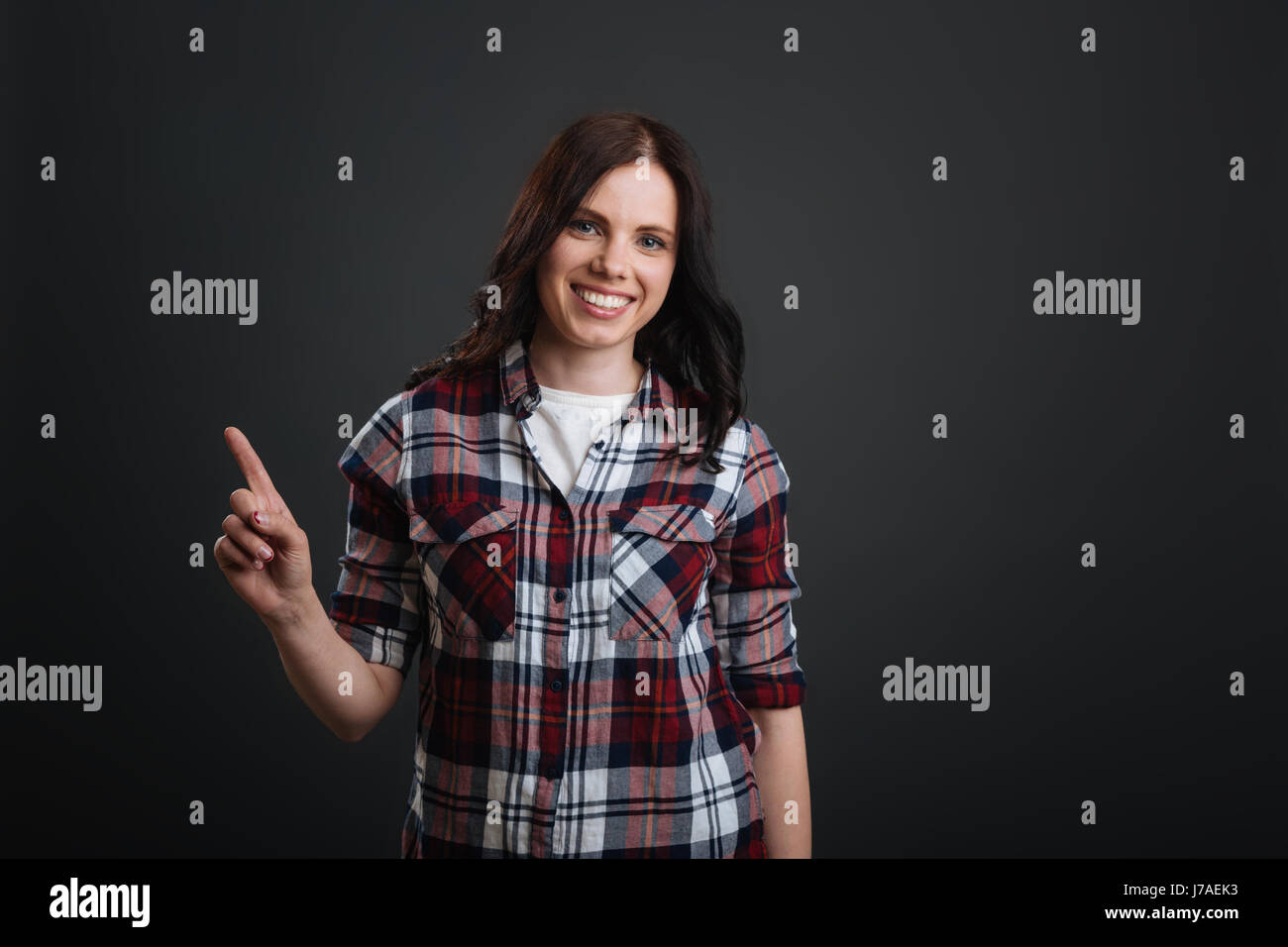 Positive clever woman pointing at something with her finger Stock Photo ...