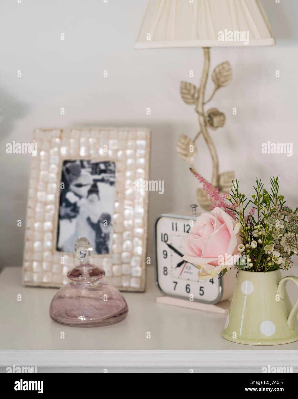 Detail of bedside table with alarm clock, framed photograph and posey ...