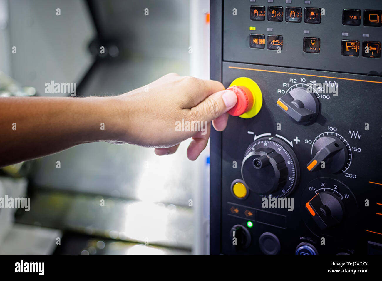A Tumb ready to press emergency Stop button on Control panel of CNC ...