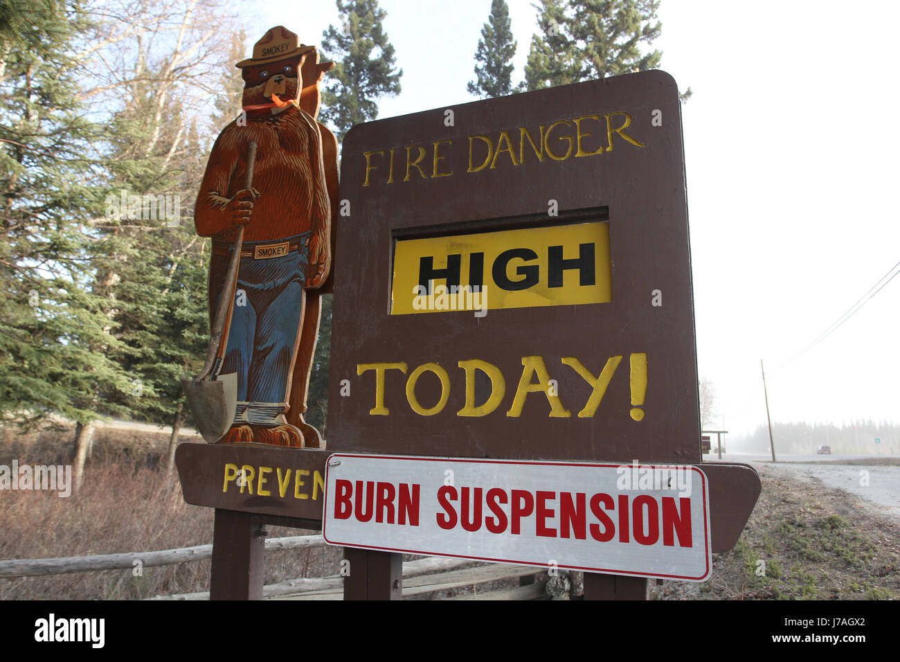 A Smokey the Bear sign warns of high fire danger and a burn suspension ...