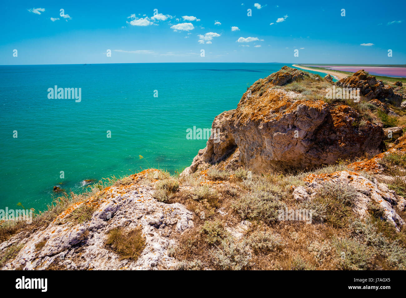 View of the open sea. Rocky seashore with blue sky. Pink lake near the ...