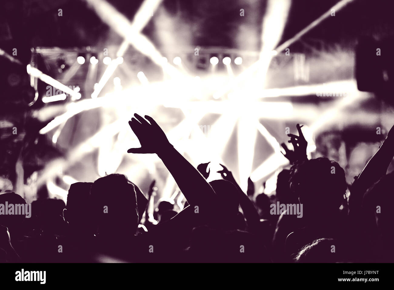 Crowd of audience with hands raised at a music festival. Lights ...