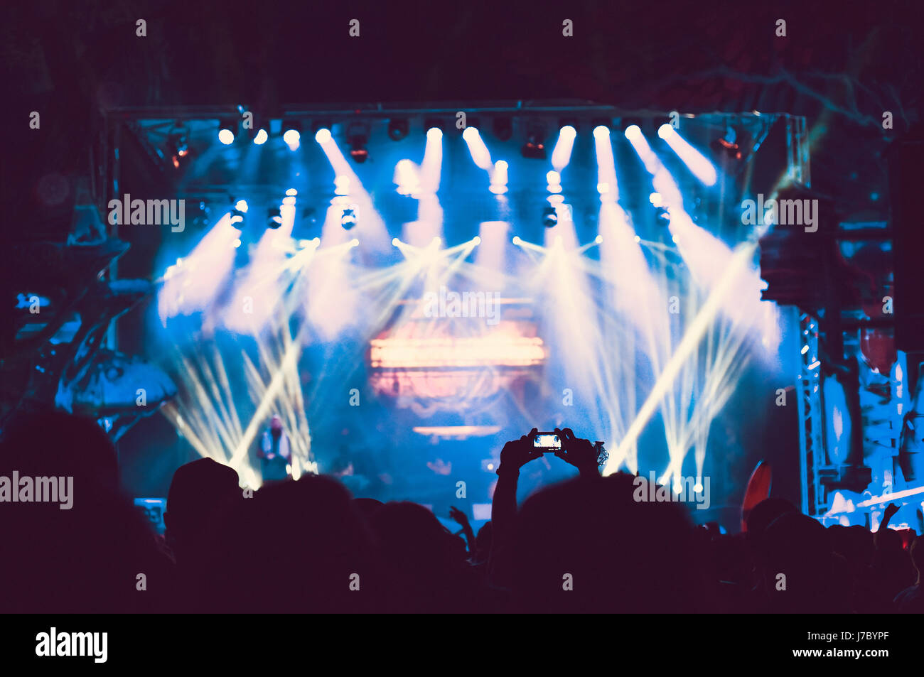 Crowd of audience with hands raised at a music festival. Lights ...