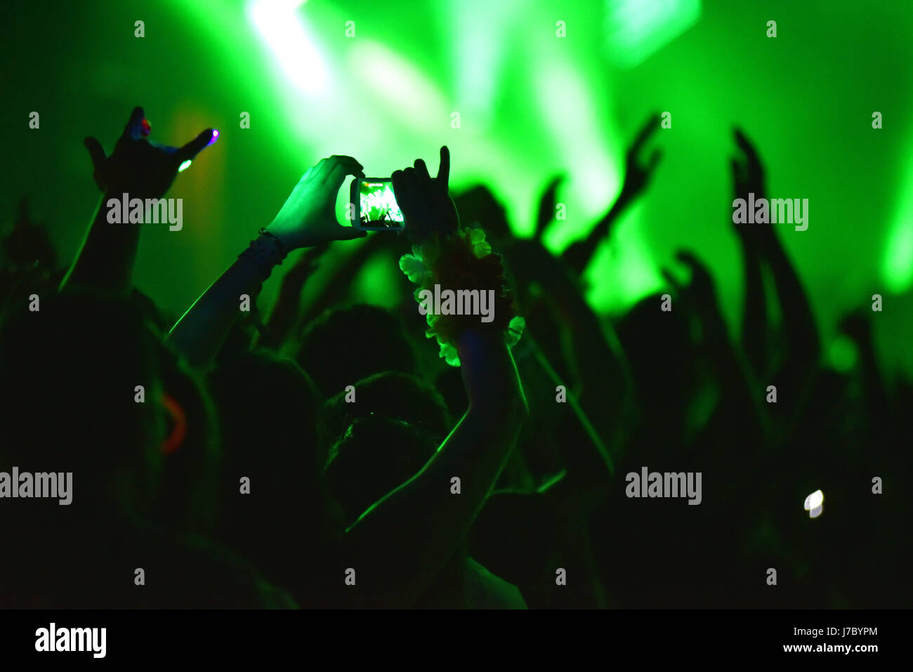 Crowd of audience with hands raised at a music festival. Lights ...