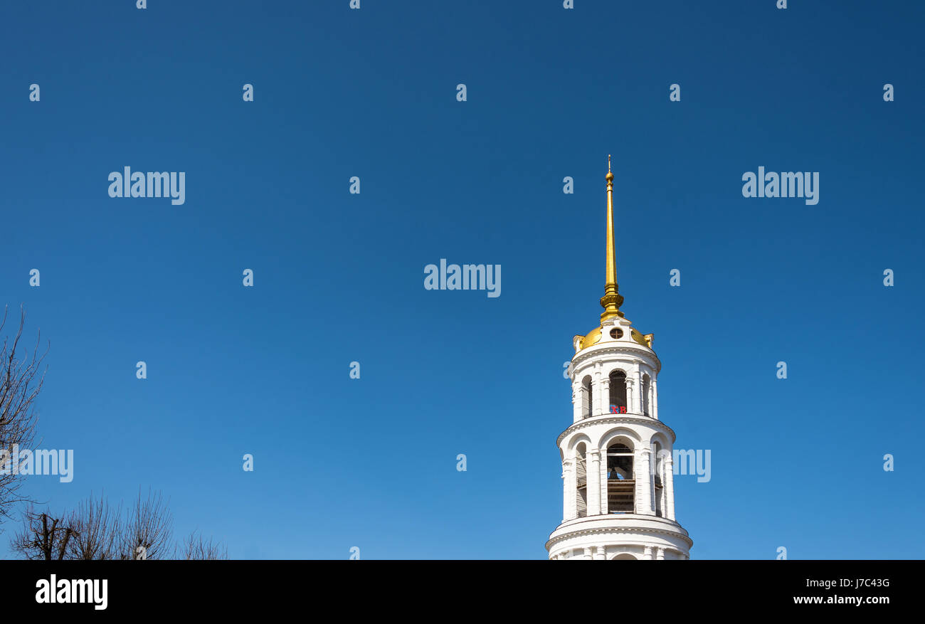 High white bell tower with a tall Golden spire in the town of Shuya ...