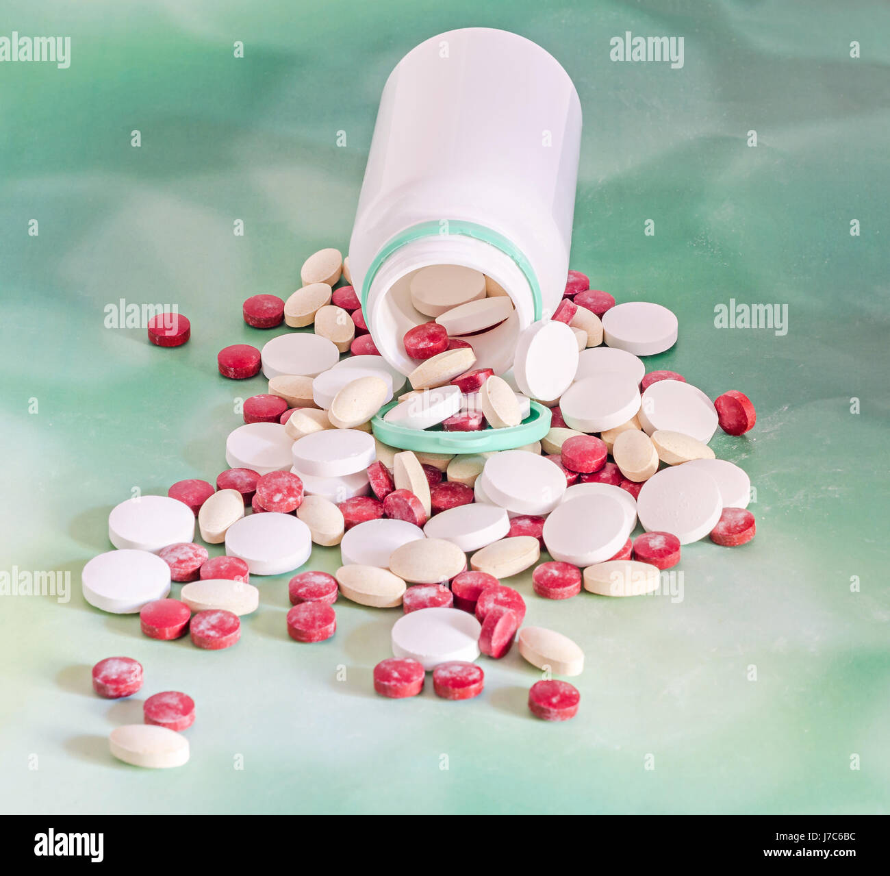 Red, white, yellow drugs pills with white open plastic bottle, powder ...