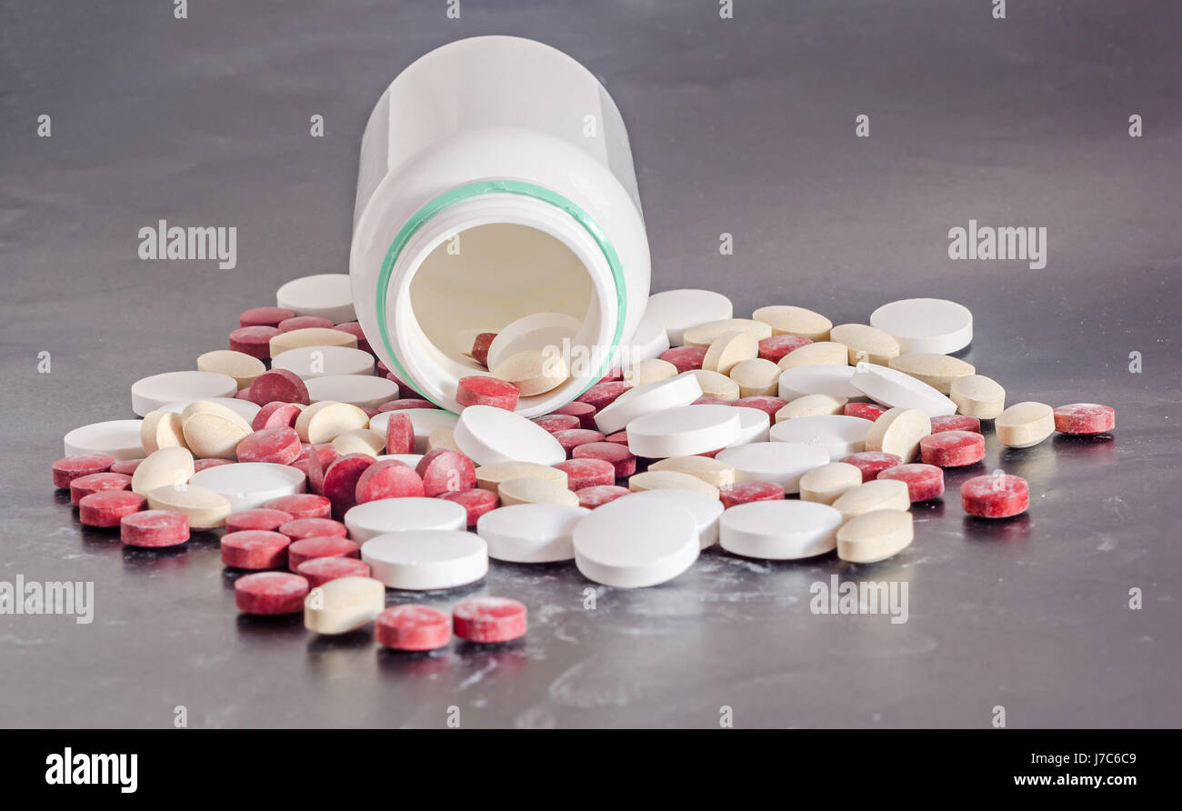 Red, white, yellow drugs pills with white open plastic bottle, powder ...