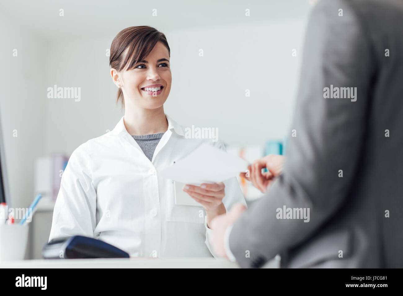 Male customer at the pharmacy, he is giving to the smiling pharmacist a ...