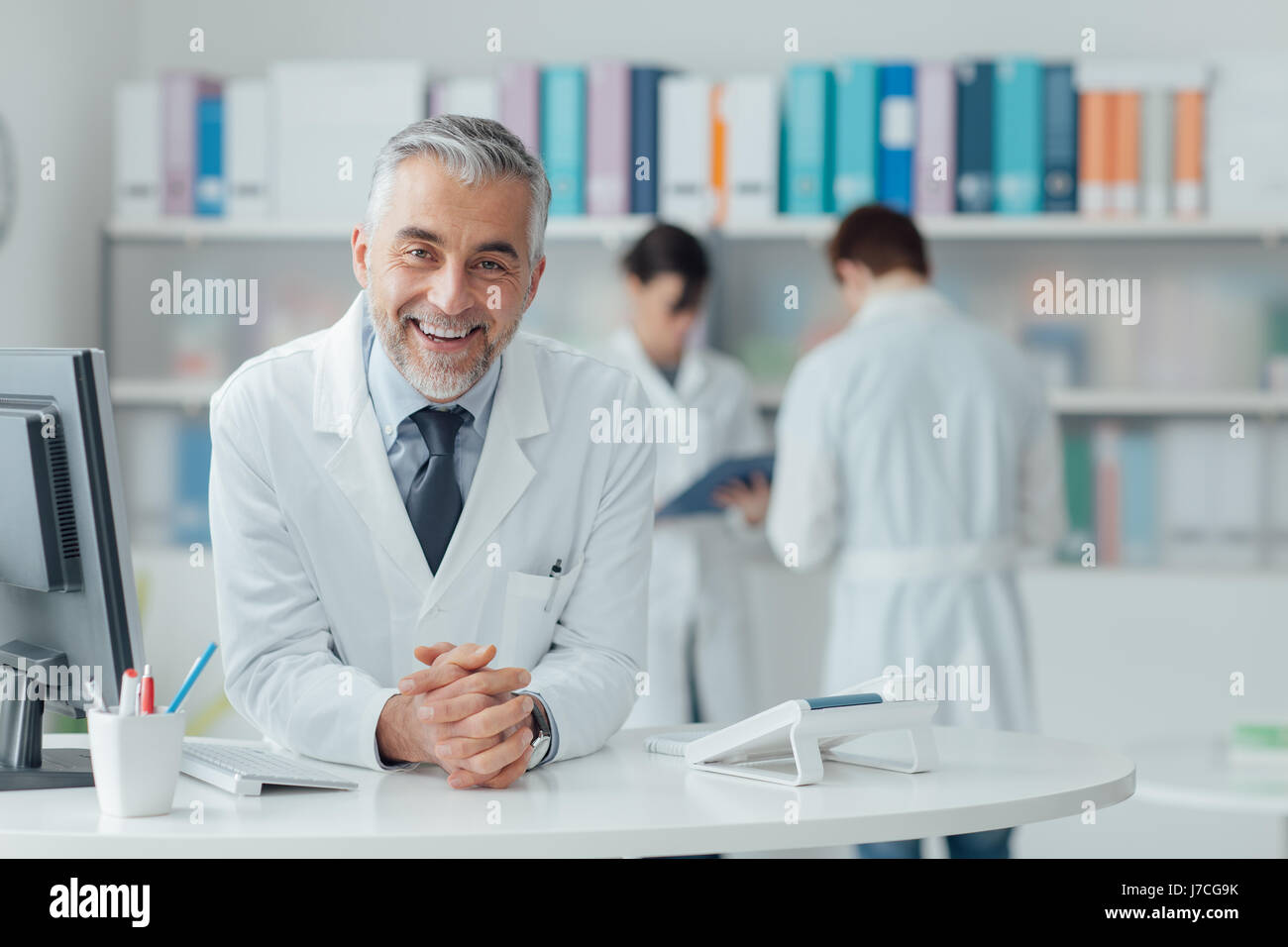 Smiling confident doctor at the reception desk, medical staff working ...