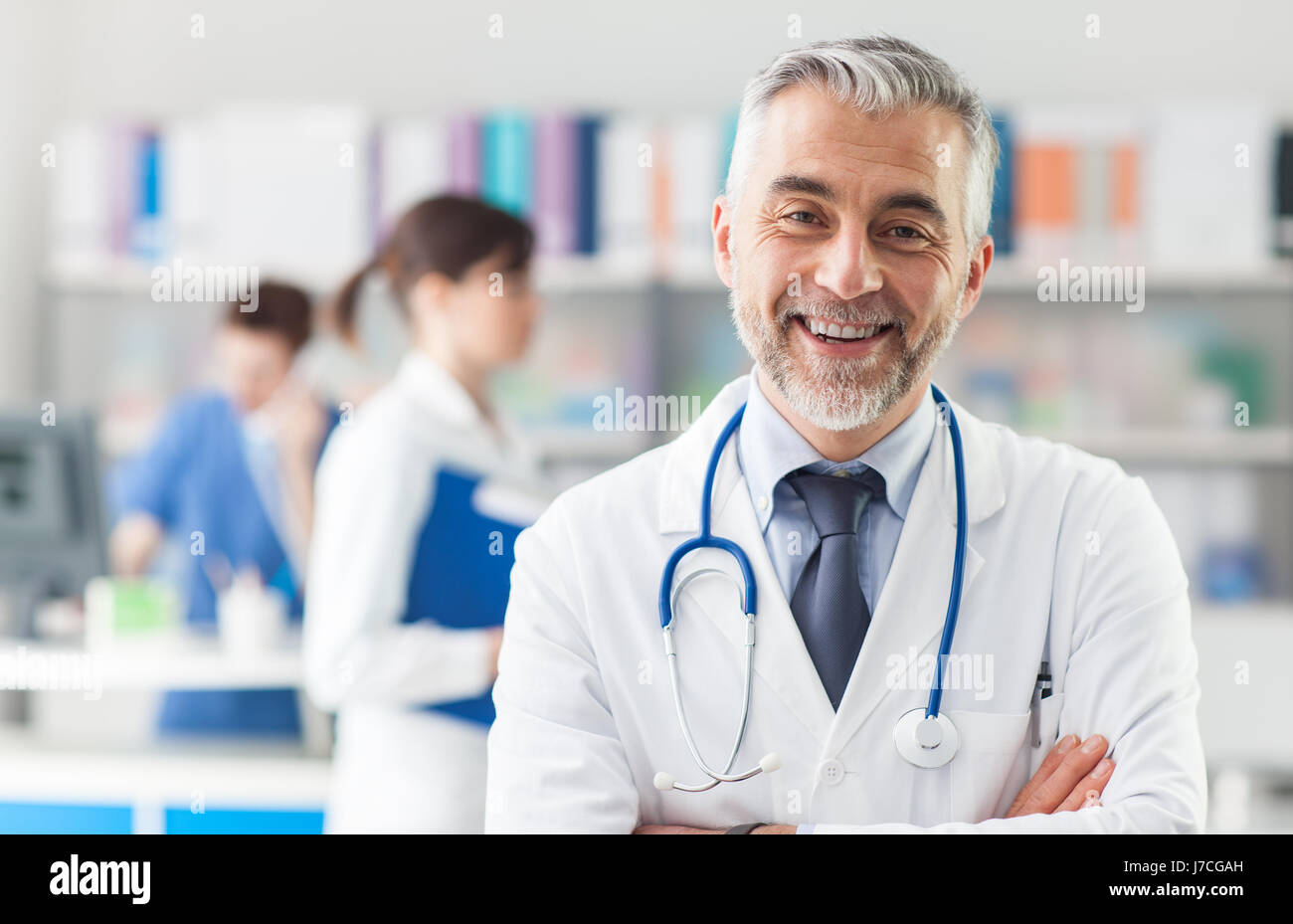 Smiling doctor posing with arms crossed in the office, he is wearing a ...