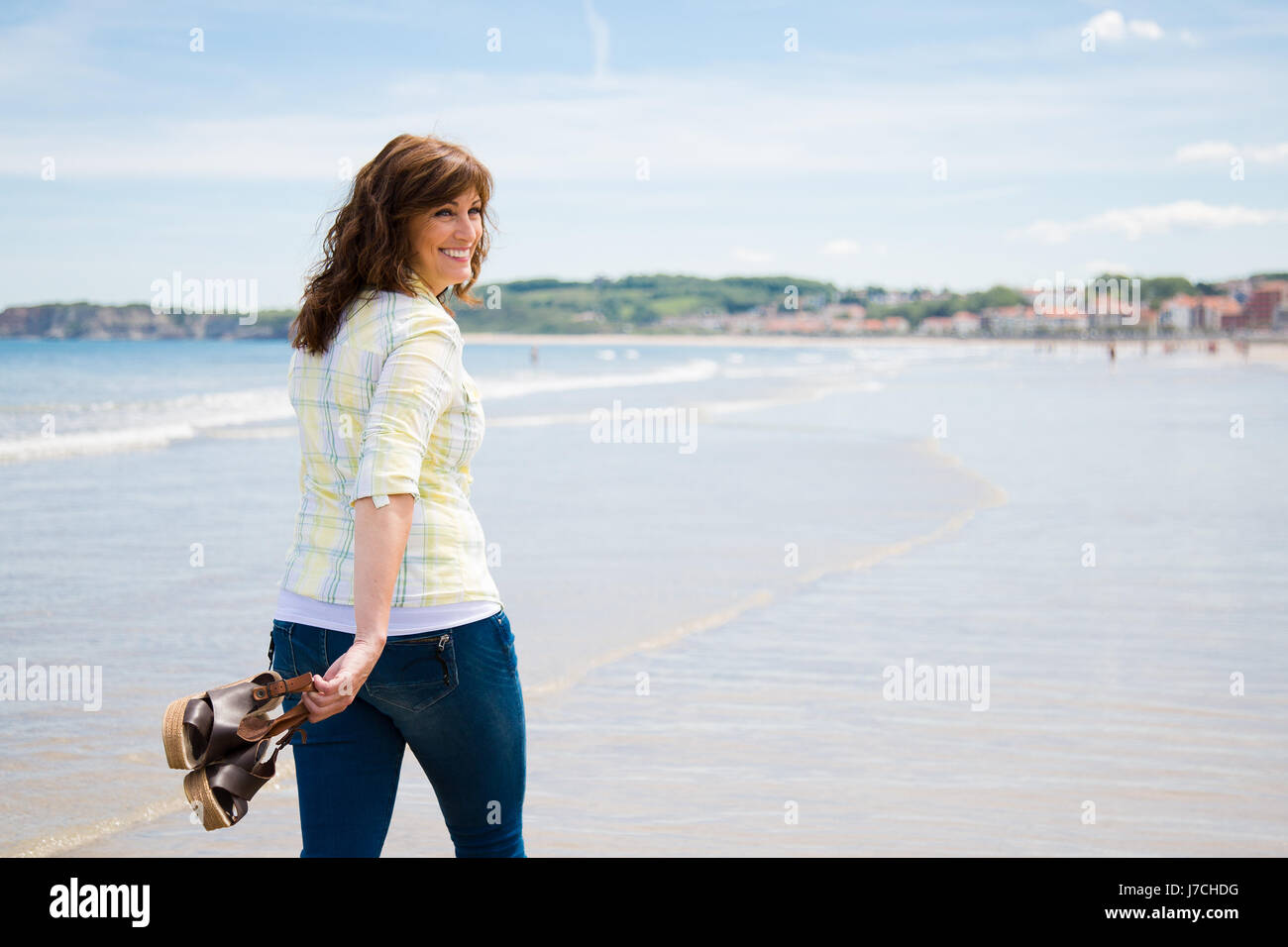 Attractive and happy middle aged woman walking along the seashore ...
