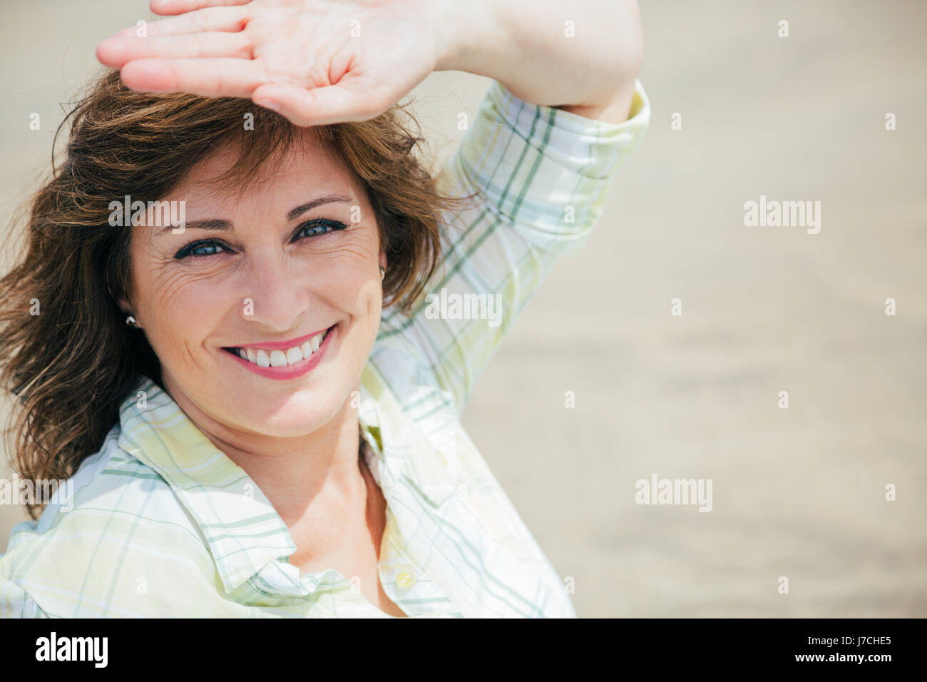 Beautiful middle aged woman protecting face from sun with hand on the ...