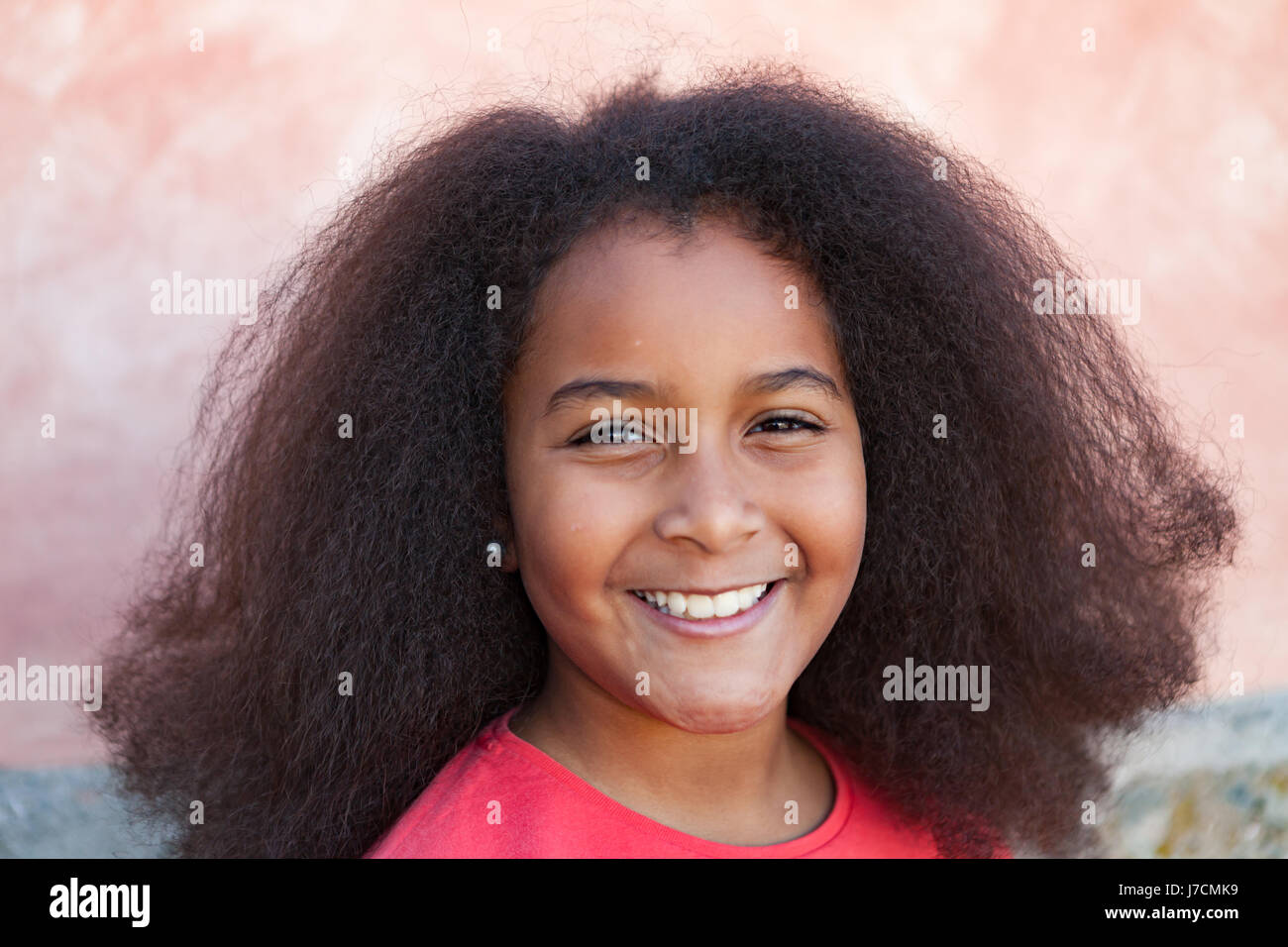 Pretty girl with long afro hair in the garden laughing Stock Photo - Alamy