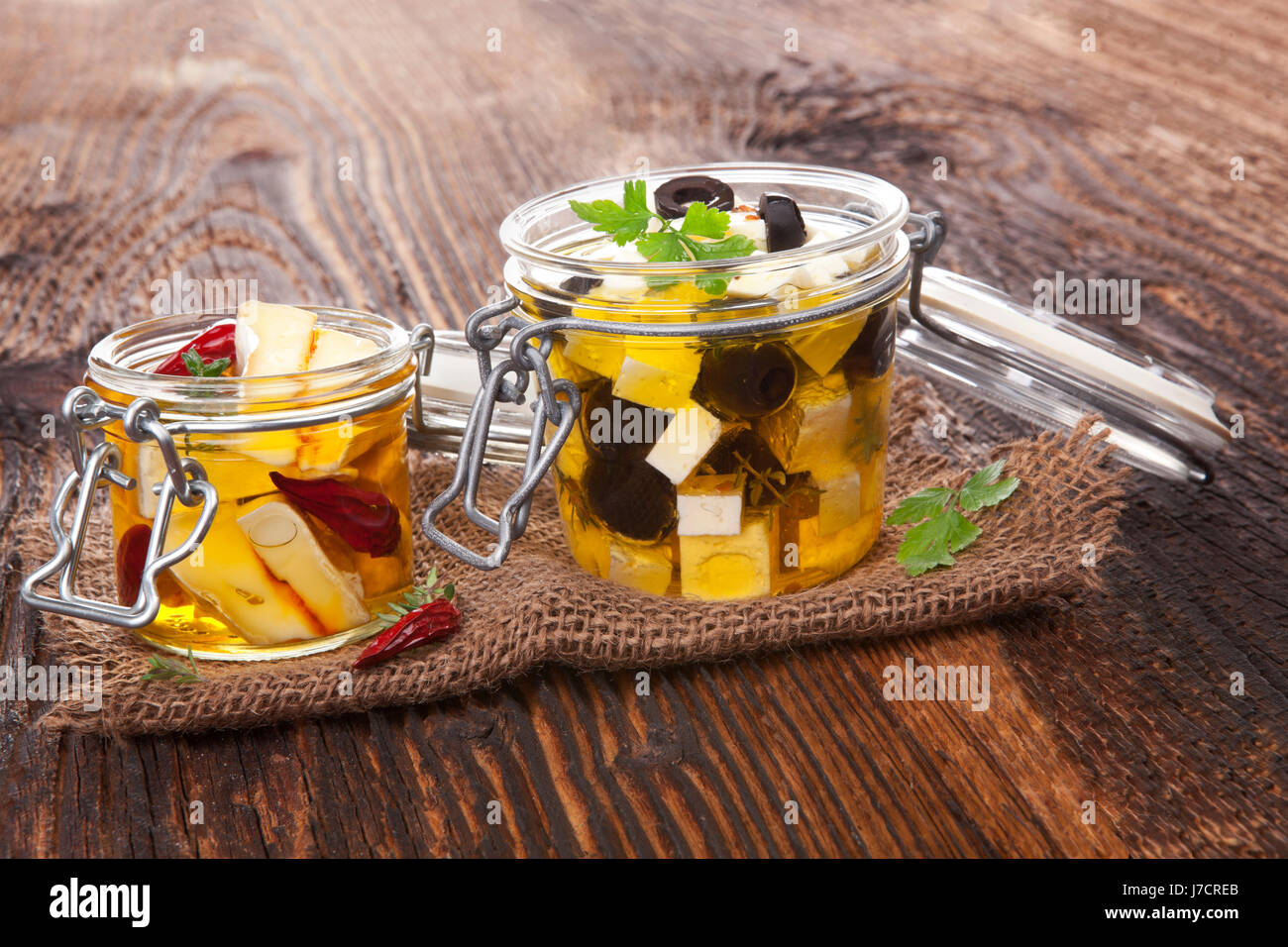 Camembert cheeses in glass with oil on wooden table. Preserved cheese ...