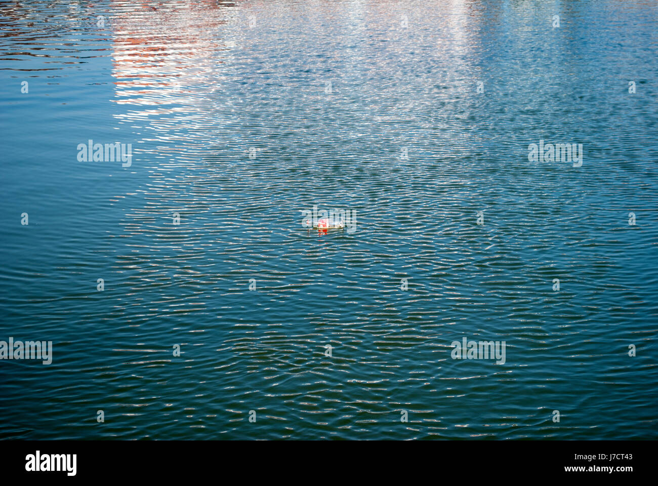 Empty coke bottle floating on water Stock Photo - Alamy