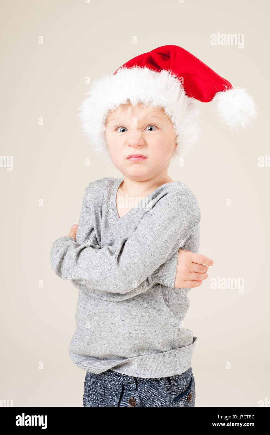 Boy with red Chistmas hat making a grumpy face Stock Photo - Alamy