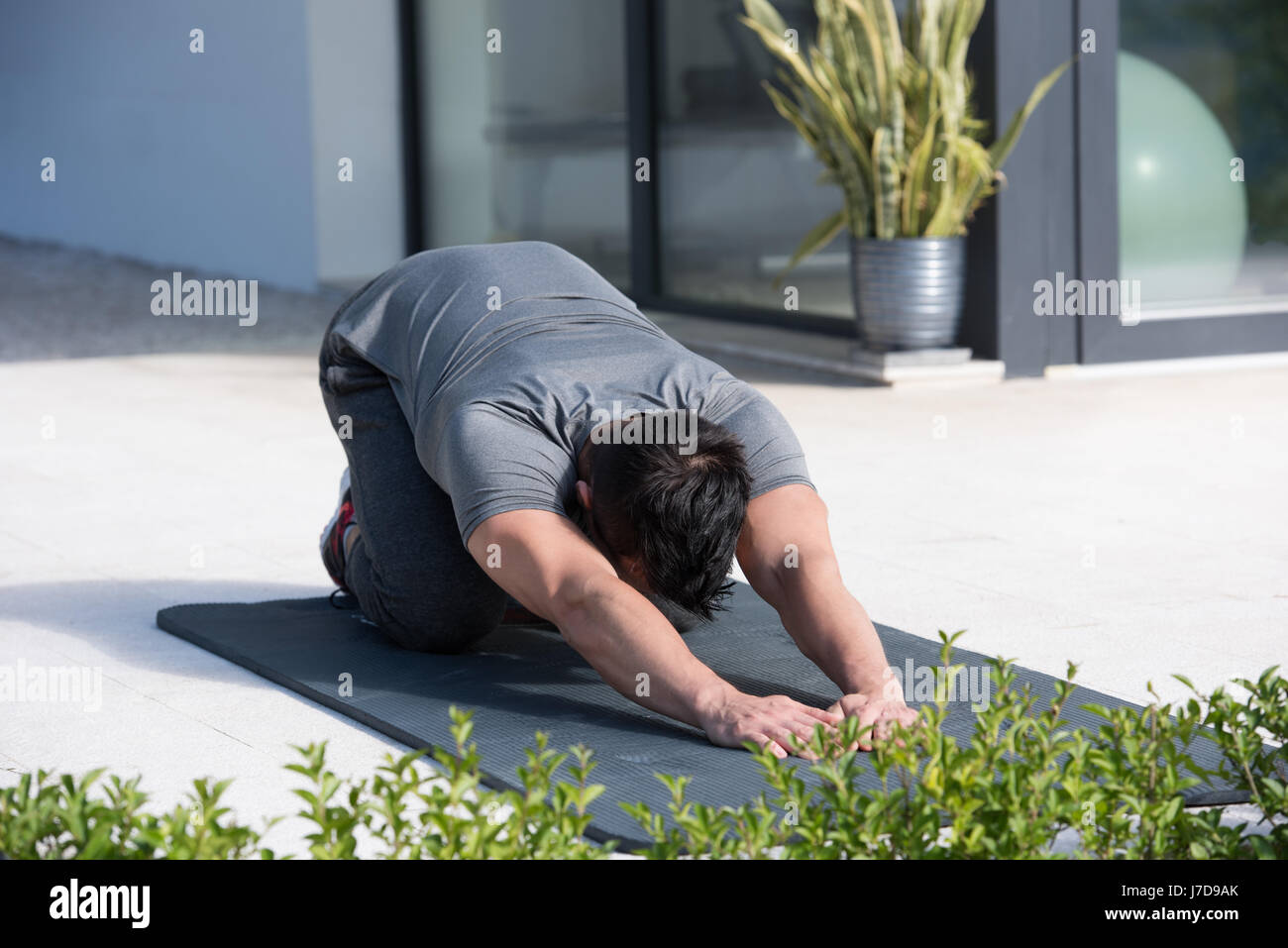 young handsome man doing morning yoga exercises in front of his luxury ...