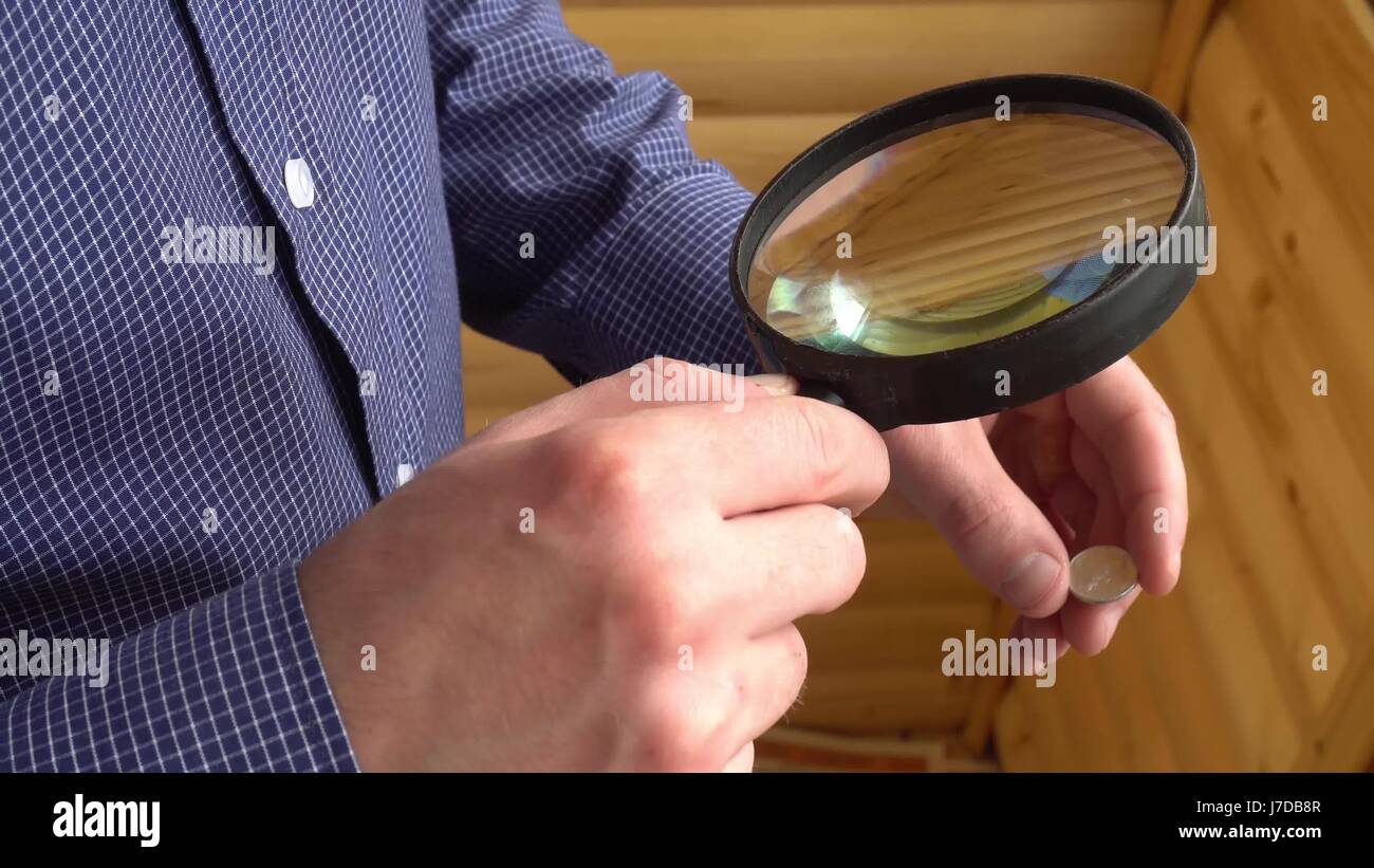 numismatist considers old coins through magnifying glass Stock Photo ...