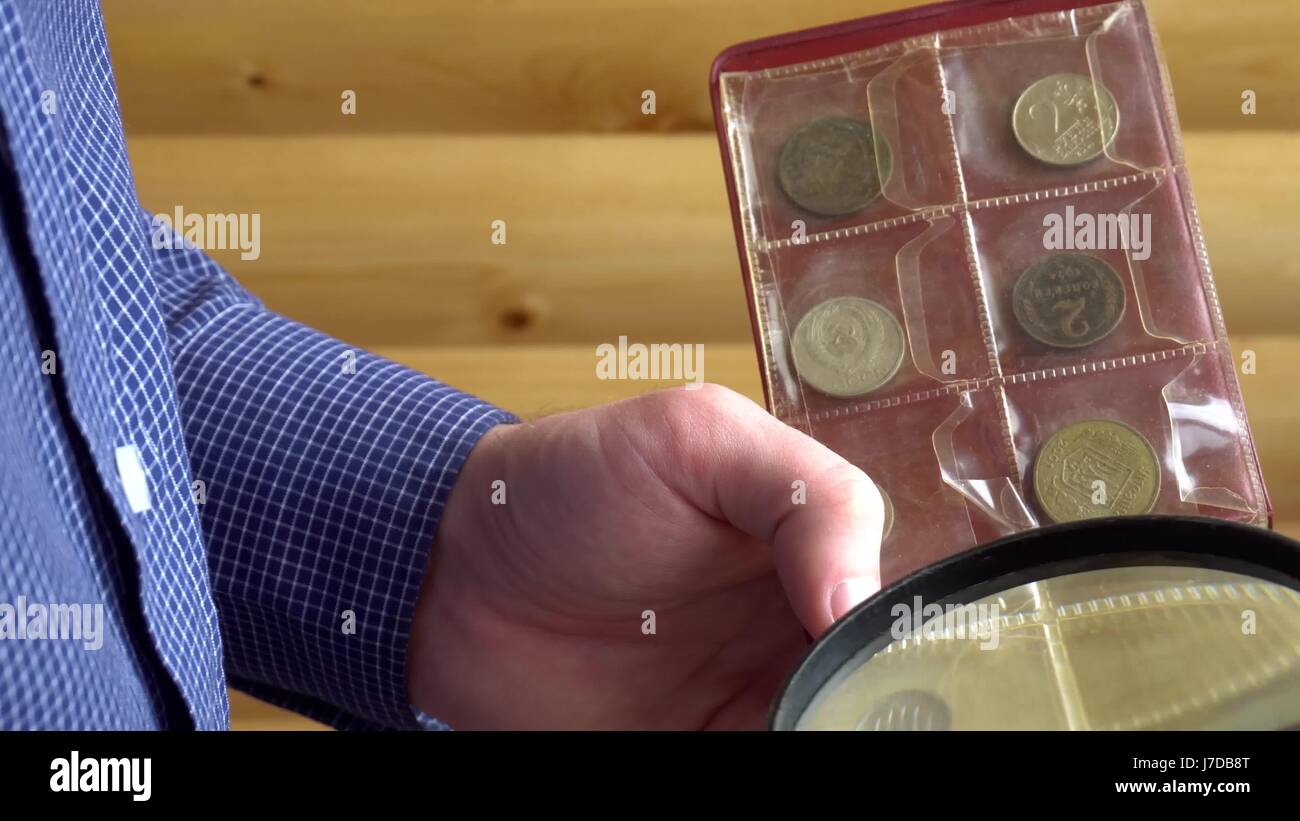 numismatist considers old coins through magnifying glass Stock Photo ...