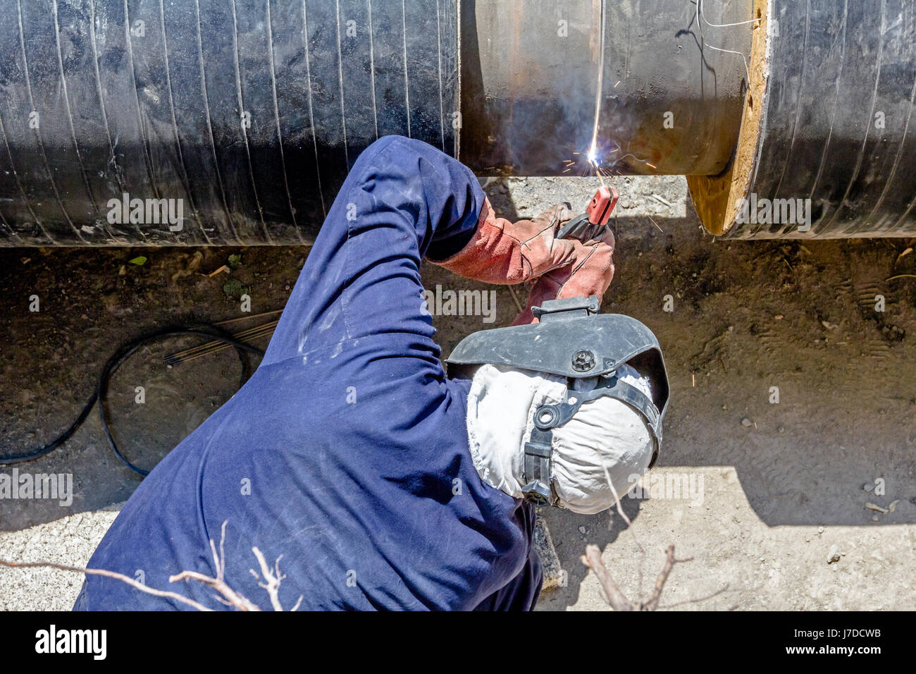 Welder is in trench working hard, arc welding pipeline Stock Photo - Alamy
