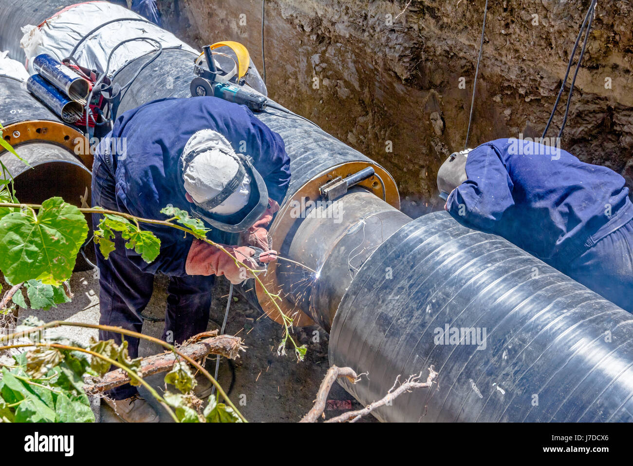 Team of welders is in trench working hard to install a new pipeline ...