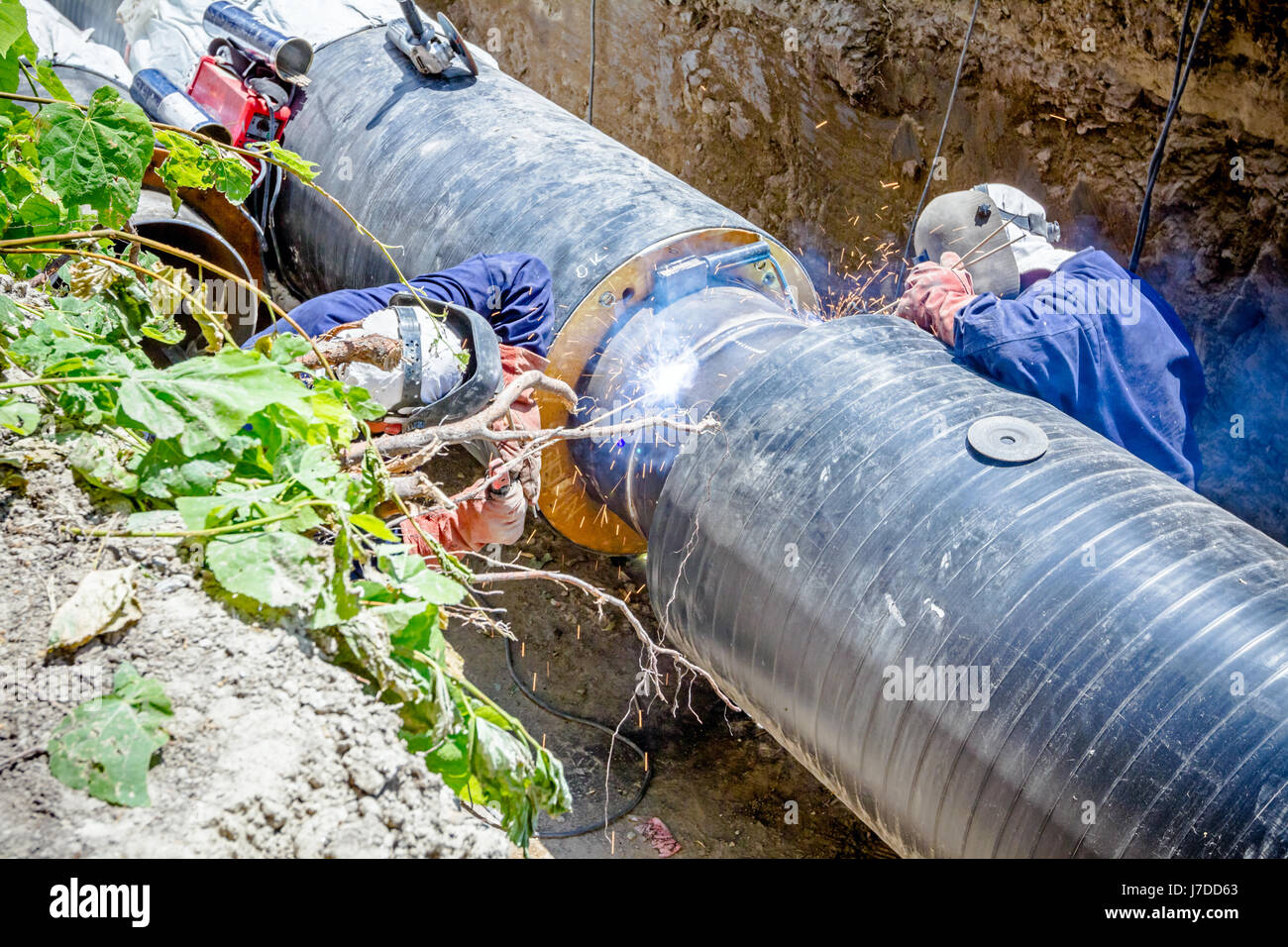 Team of welders is in trench working hard to install a new pipeline ...