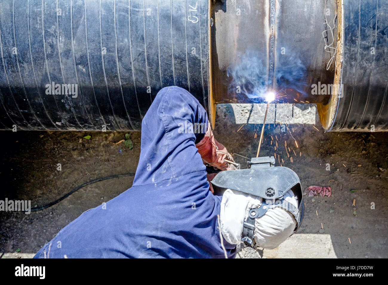 Welder is in trench working hard, arc welding pipeline Stock Photo - Alamy