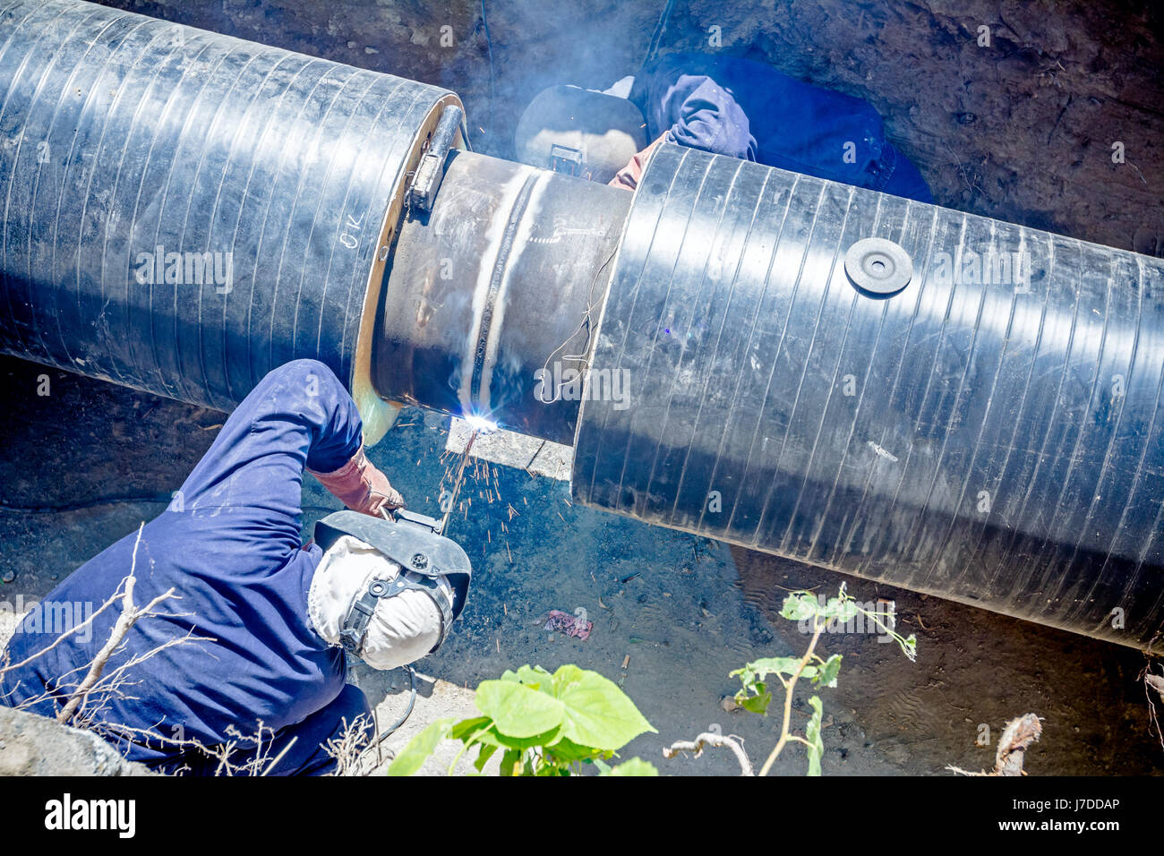 Team of welders is in trench working hard to install a new pipeline ...