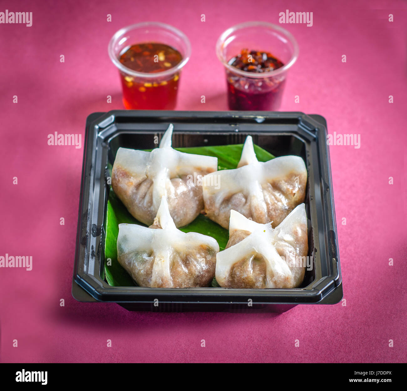 dim sum with chilly sauce on a pink background Stock Photo - Alamy