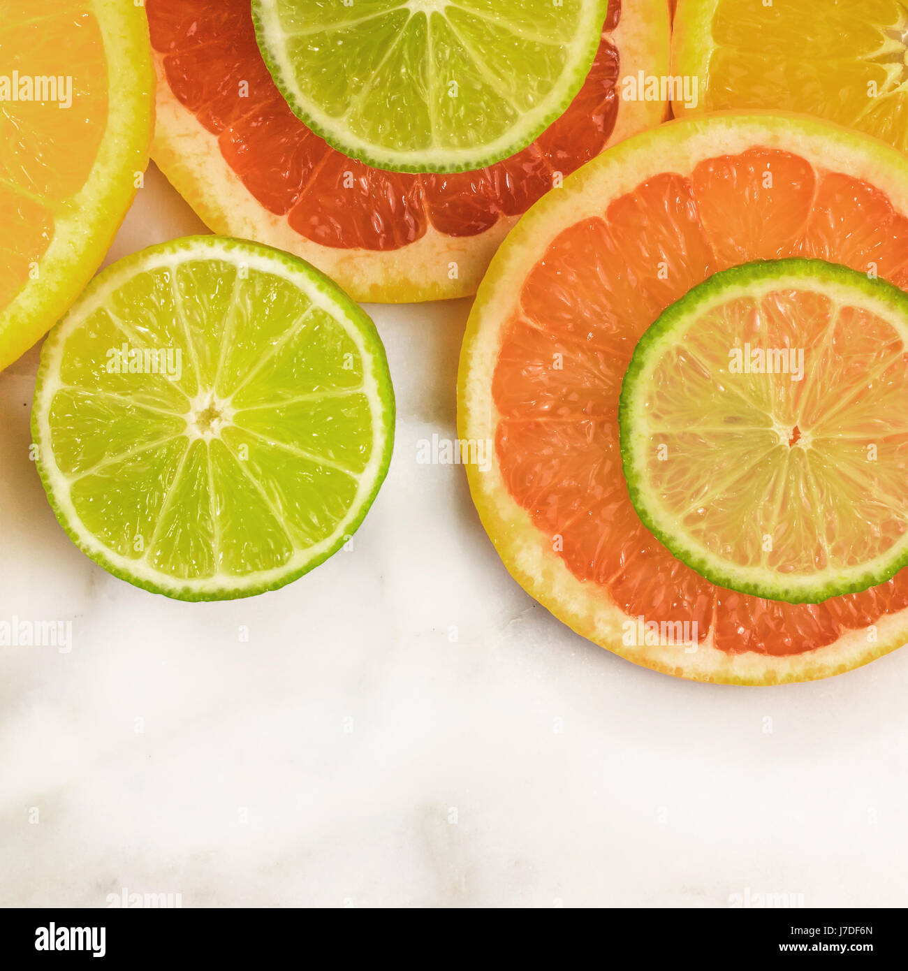 Vibrant juicy citrus fruits on a white marble texture with copy space ...