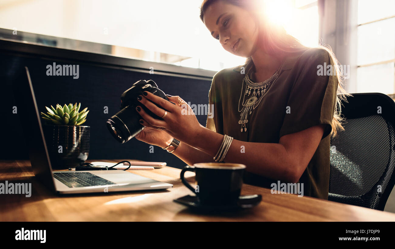 Young woman looking at camera while working on laptop. Photographer ...