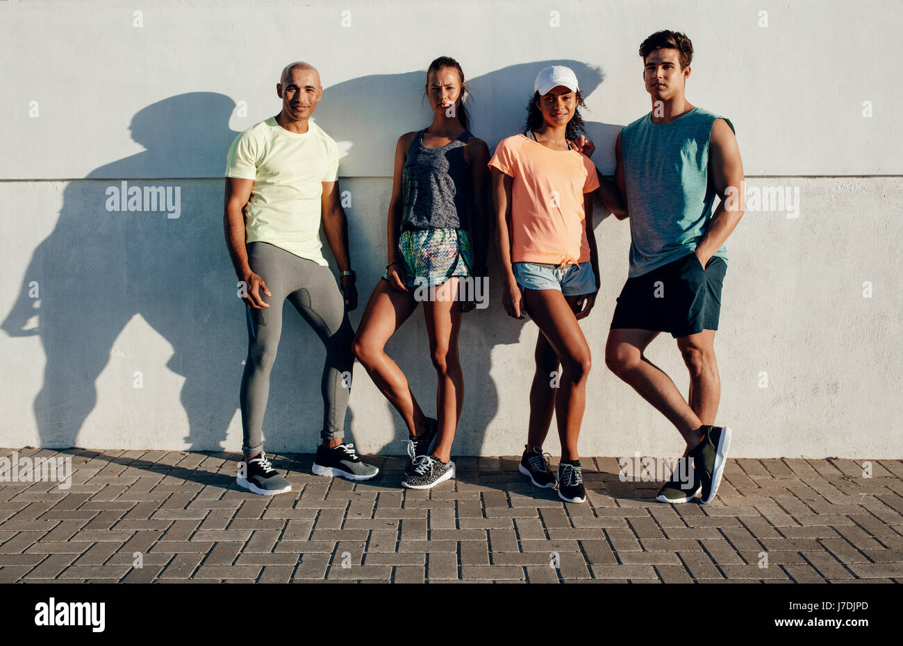 Full length shot of young people standing together by a wall. Group of ...