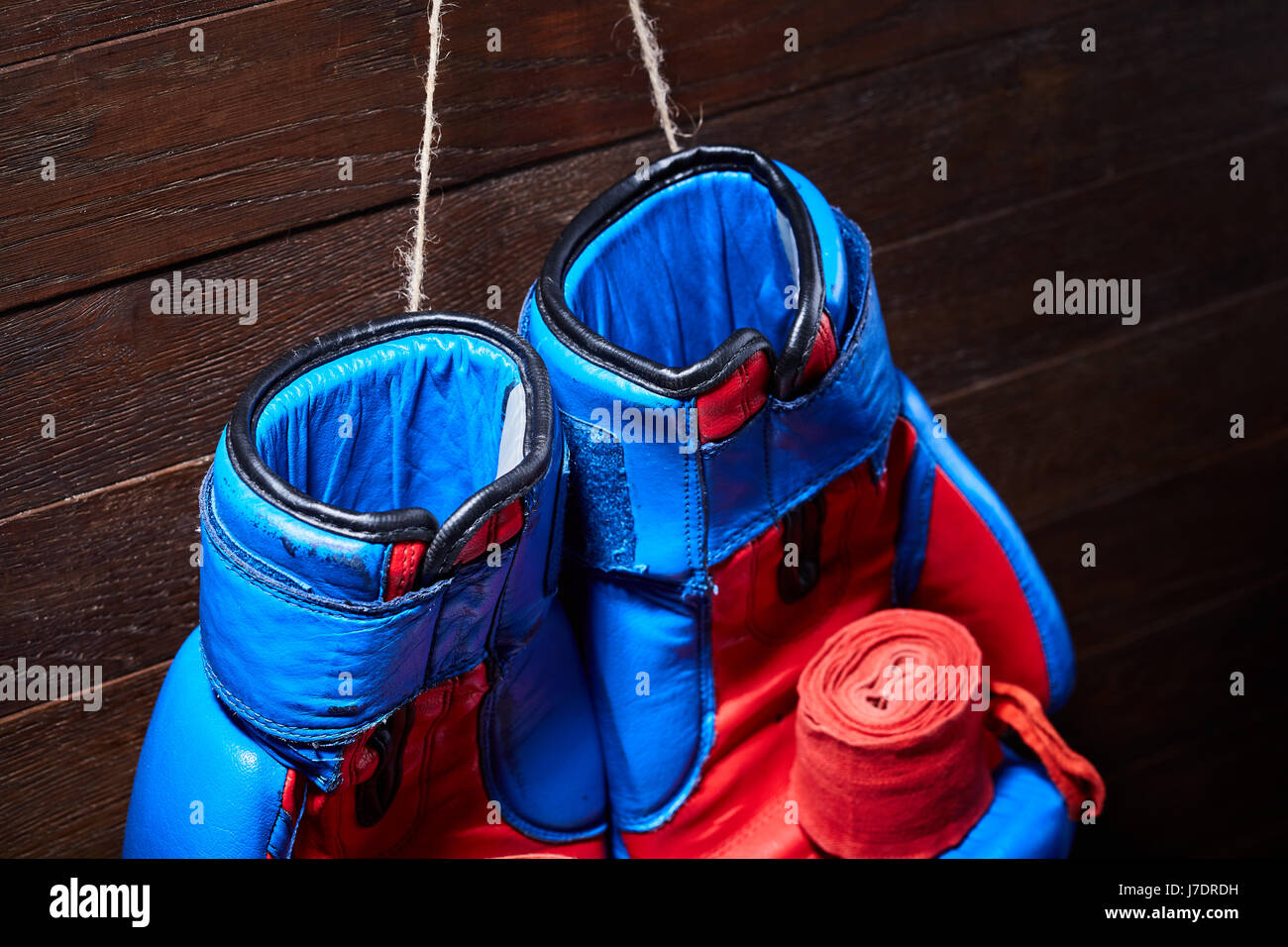 Blue and red boxing gloves and bandage on brown plank background ...